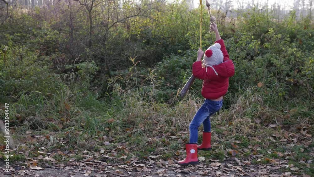 Little girl in nature park unexpectedly falls from a swing on ground ...