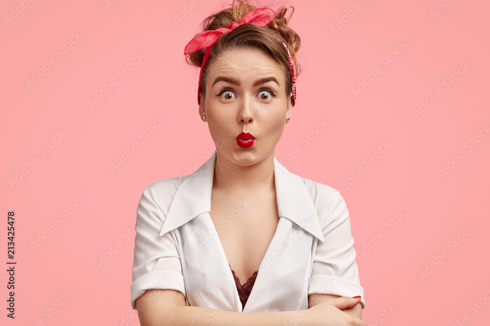 Stunned young female with surprised expression, keeps red lips round ...