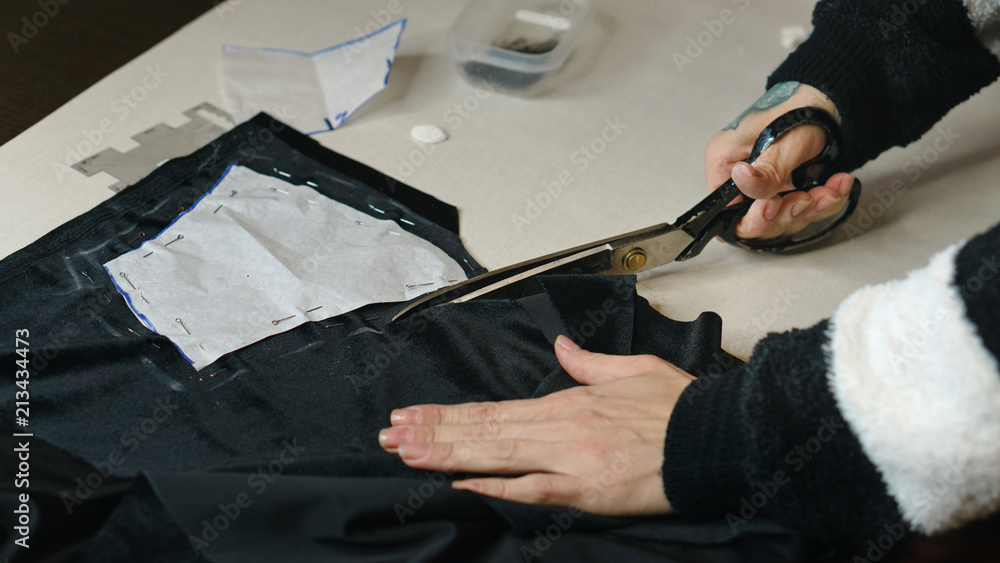 Girl modeler cuts a scissor pattern on the fabric. Shooting close-up ...