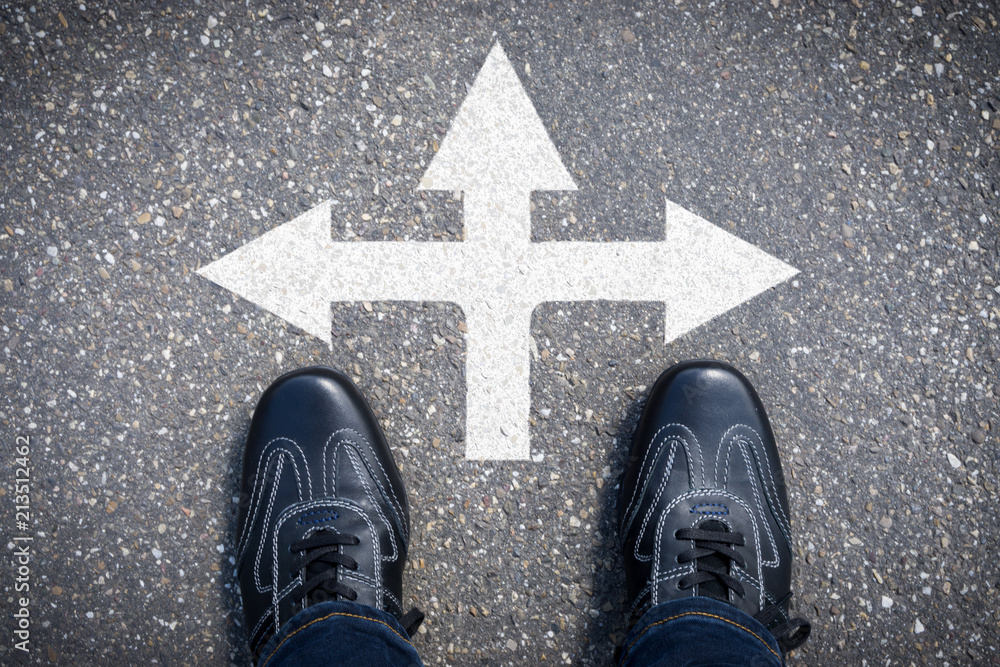man standing on road with three direction arrow choices, left, right or ...
