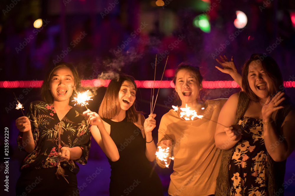Sparklers with group of friends having fun for celebration and hand ...