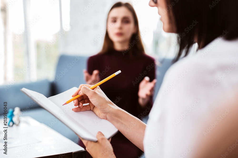 Making notes. Emotional young patient describing her personal problem ...