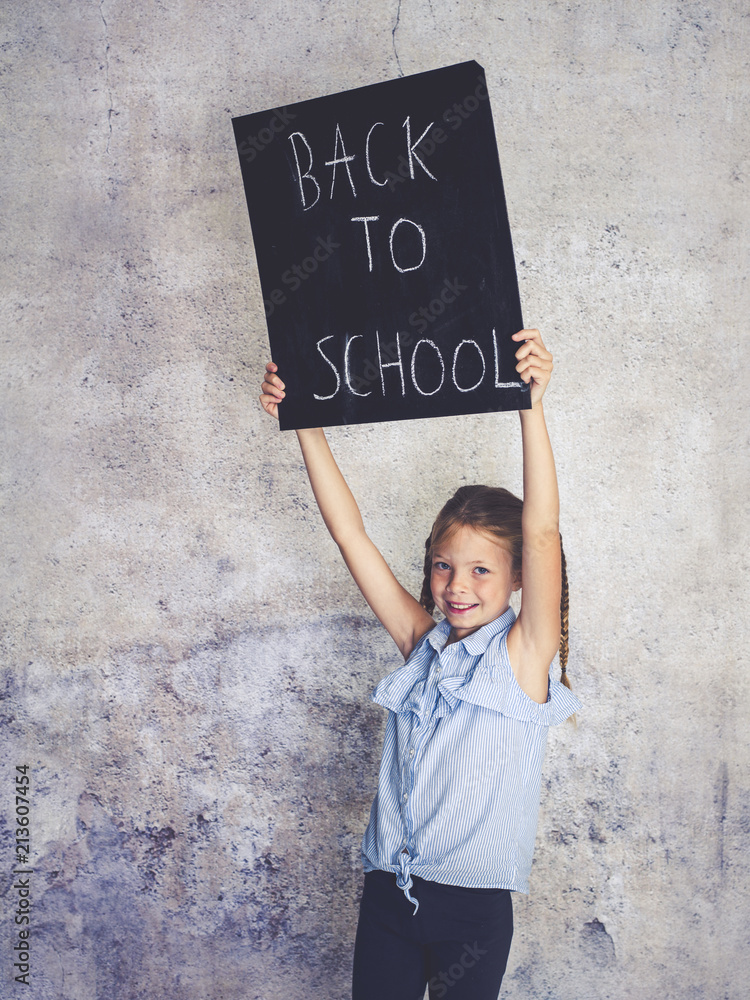 blond schoolgirl is holding blackboard with the words back to school in ...