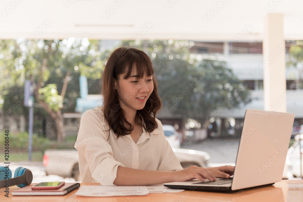 Beautiful young female student using portable laptop computer while ...