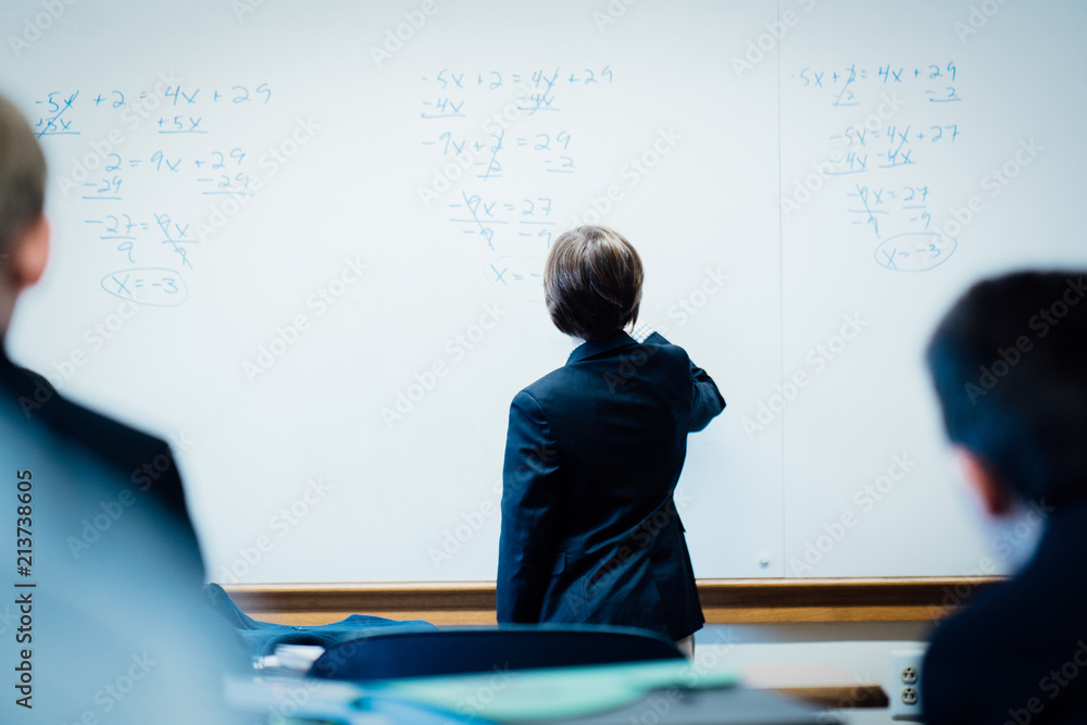 student works on math problems on whiteboard Stock Photo | Adobe Stock
