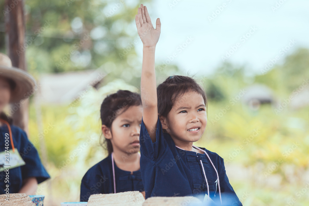 Cute asian child girl raising her hand in the air to answer the ...