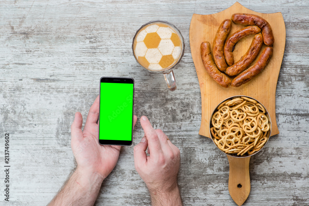 Male hand holding smartphone mobile cell phone near beer with a soccer ...
