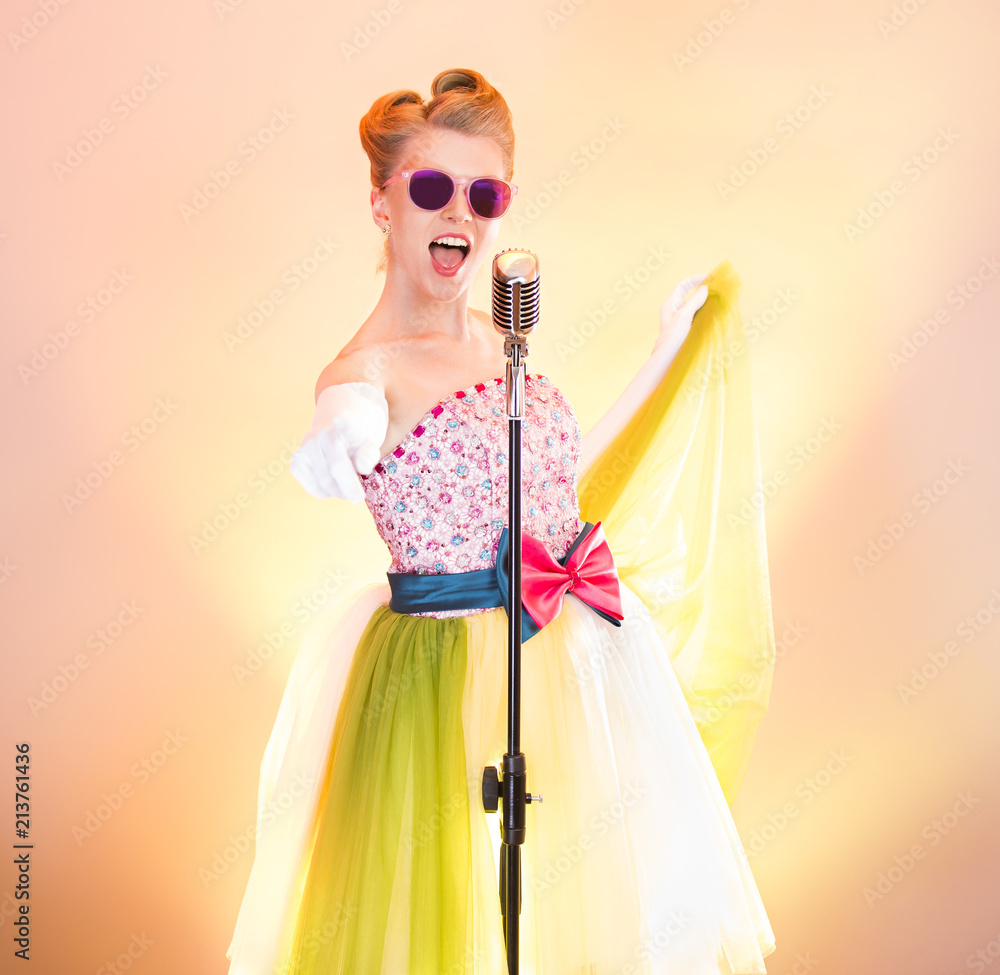 Happy girl singer in pink glasses smiles, have fun, sings into retro ...
