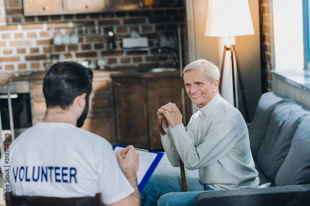 Valuable answers. Well-built dark-haired volunteer talking with an aged ...