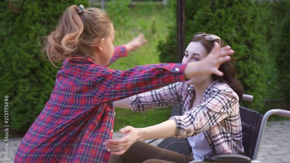 Woman with a disability in a wheelchair hugs the teenage girl.Slow mo ...