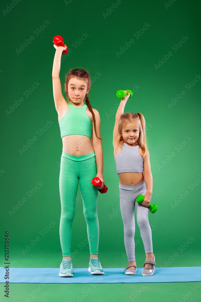 Children girls doing fitness exercises on green background together ...