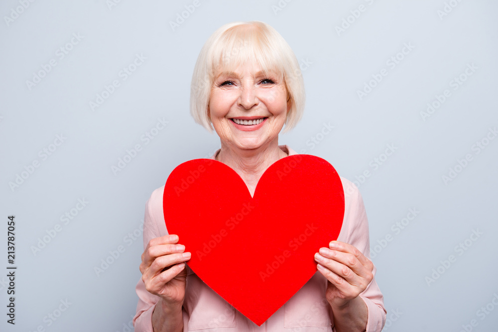 Portrait of old adult blonde caucasian glad lady holding hands big red ...