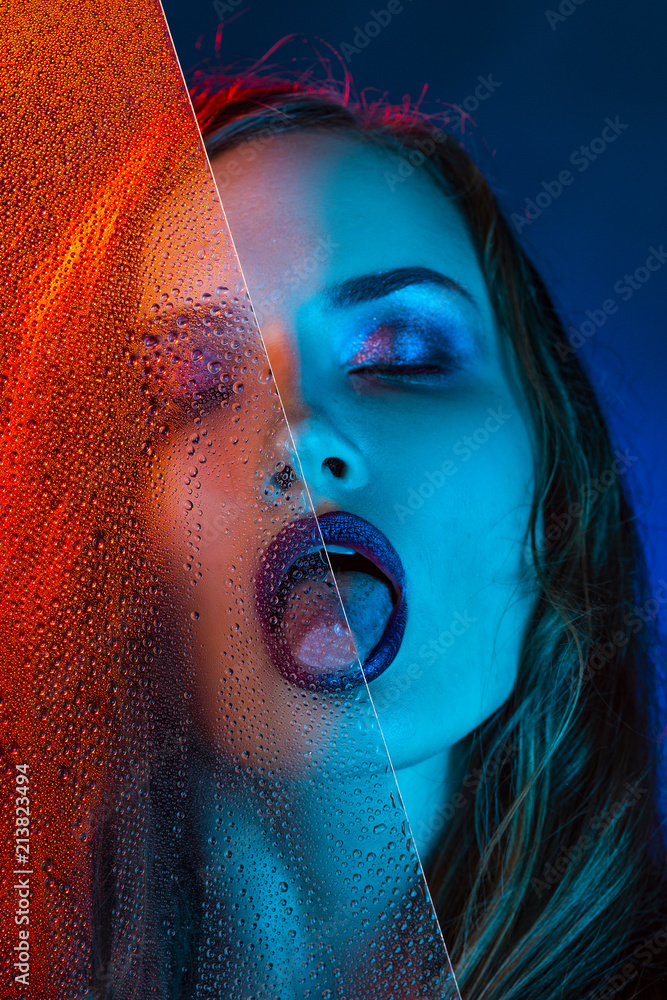 A beautiful model girl, illuminated with blue and red lights, half ...