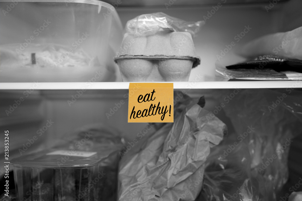 Eat healthy written on a post it note stuck on a fridge shelf with food ...