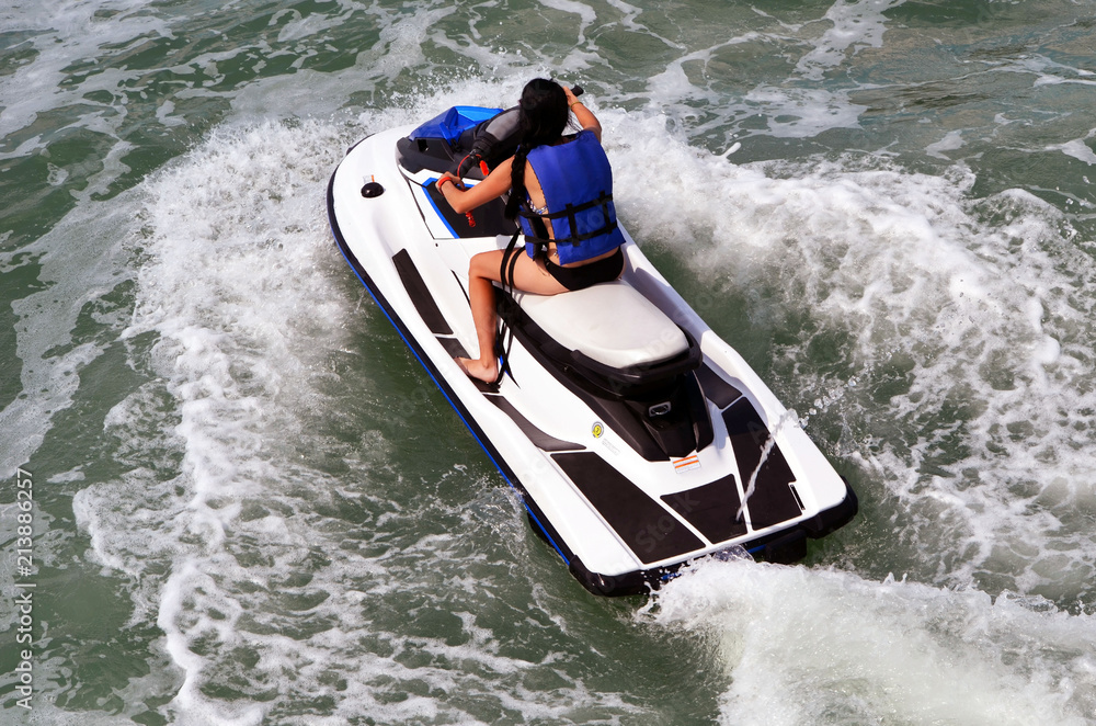 Angled overhead view of a young woman on a jet ski cruising the Florida ...