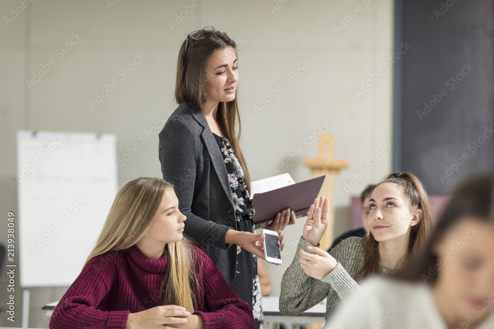 Teacher taking cell phone away from teenage girl Stock-Foto | Adobe Stock