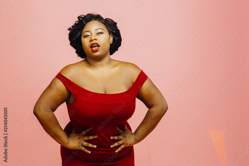 Confident curvy woman in red dress with hands on waist Stock Photo ...