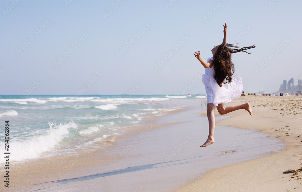 Portrait of aborable 12 years old girl jumping on the beach in summer ...