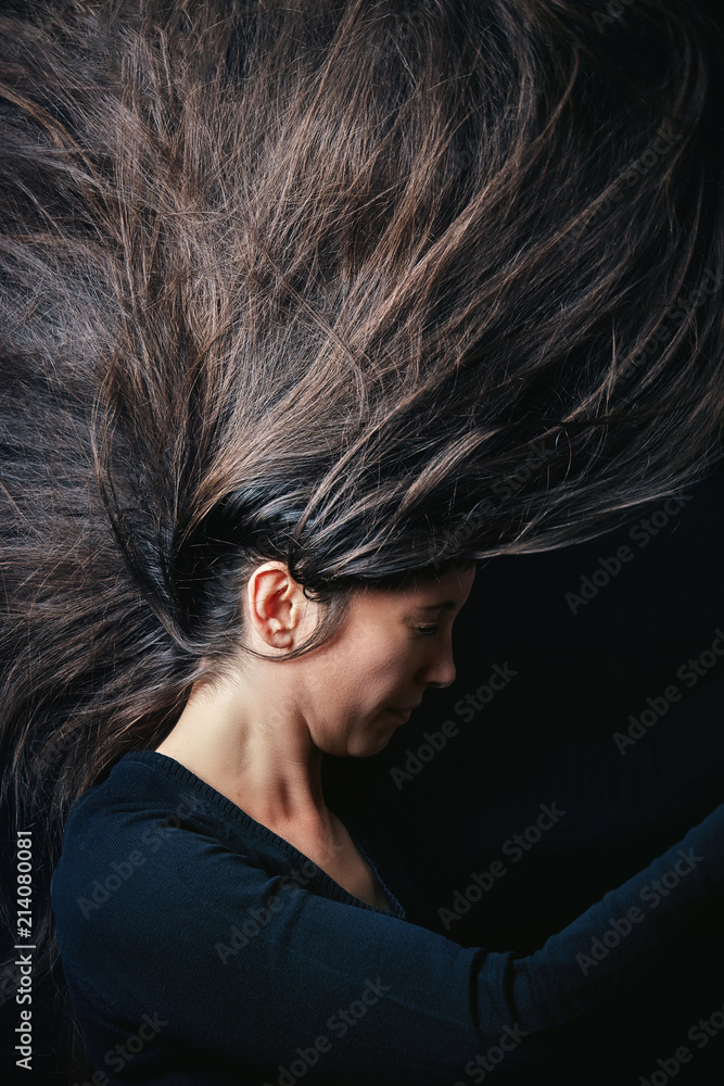 Girl throwing hair in the air on black background. Concept image for ...
