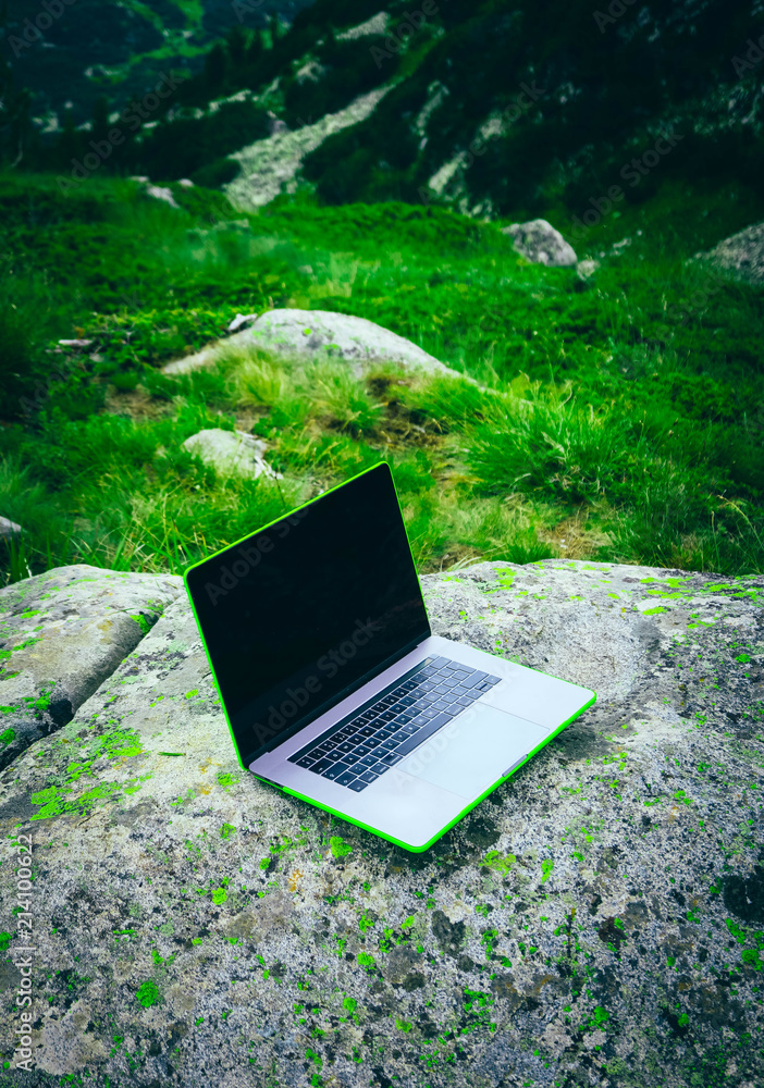 Laptop computer at the natural mountain background. Photo depicts ...