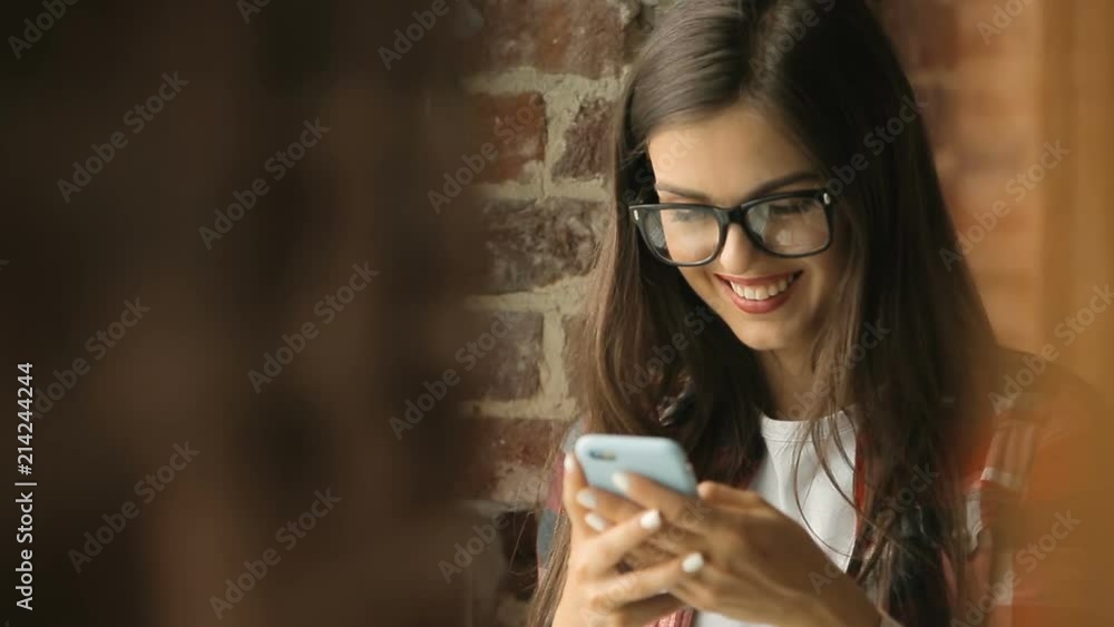 Joyful gorgeous brunette texting a message, smart woman in glasses ...