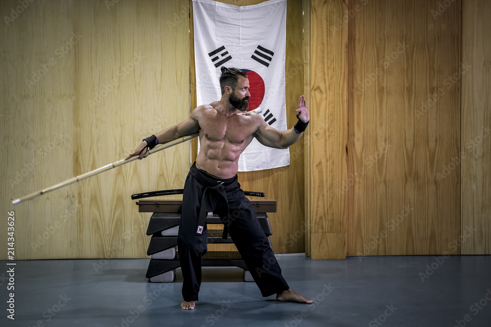 Hombre fuerte con grandes músculos entrenando artes marciales con arma ...