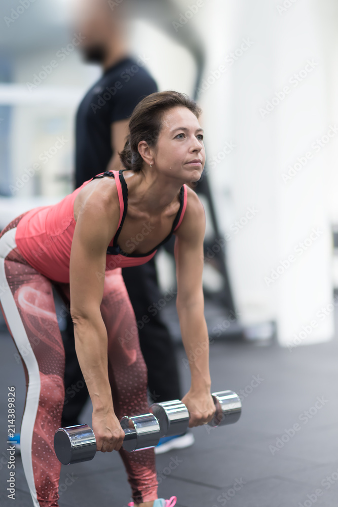 beautiful middle age woman working out in the gym training lifting ...