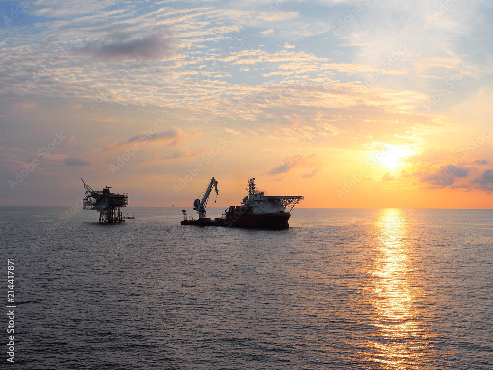 Construction support vessel positions next to static platform with sun ...