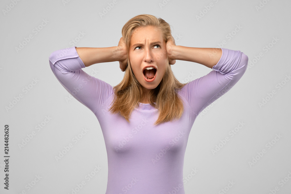 Close up of attractive blond Caucasian female yelling loudly, keeping ...