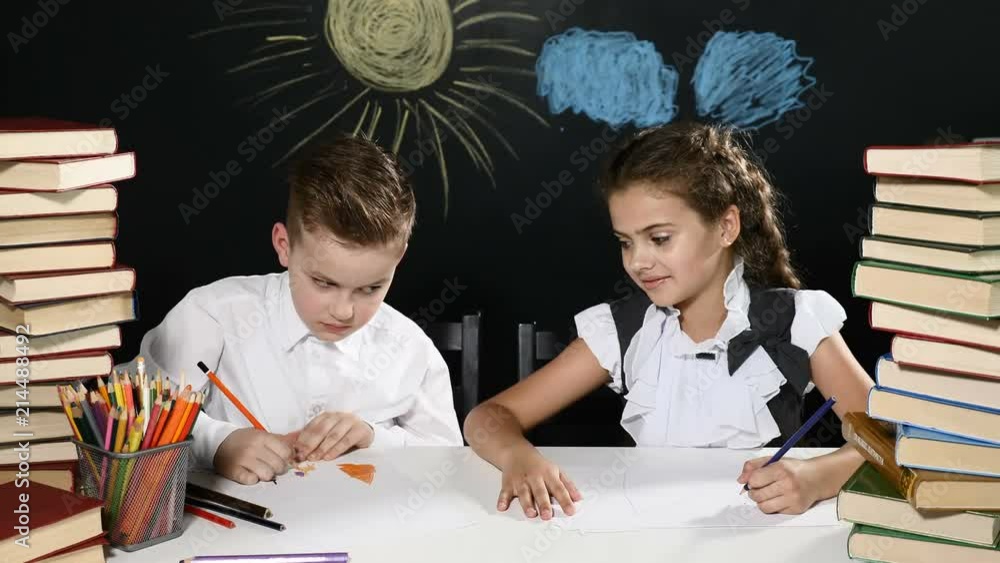 Modern school concept. Boy and girl sit at a desk with heaps of books ...