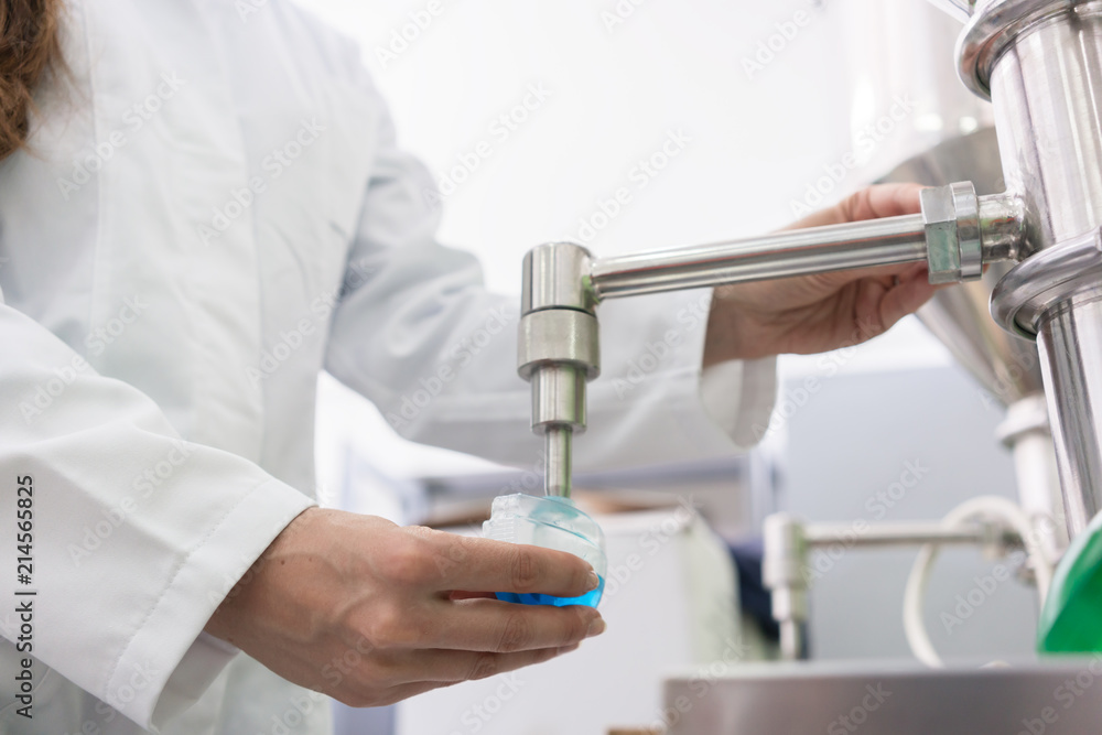 Side view close-up of the hand of a female technician filling a plastic ...