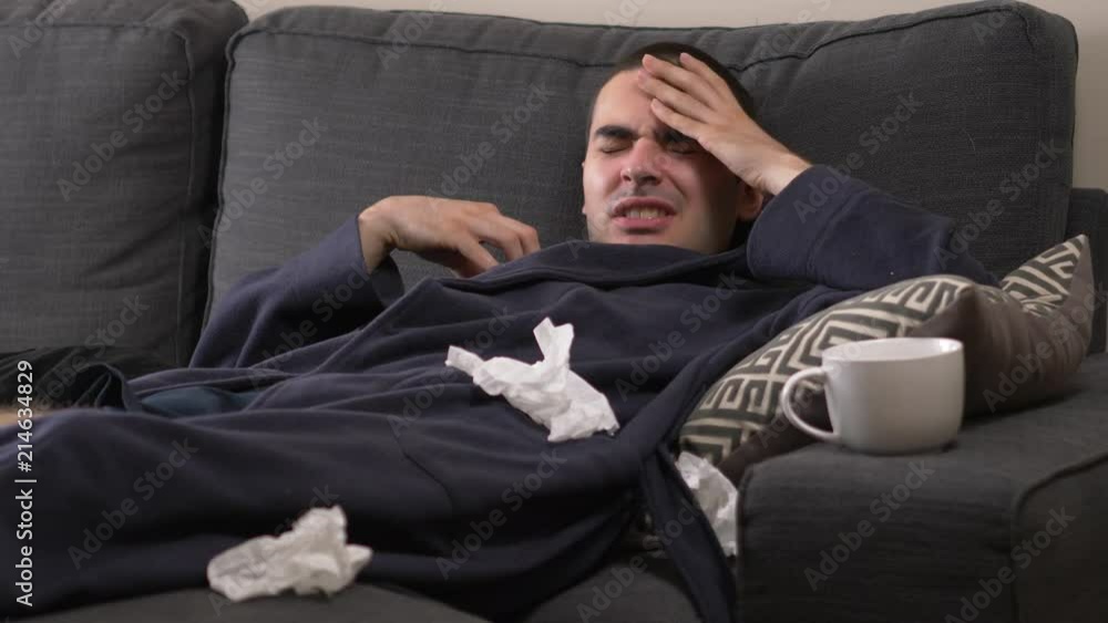 Sick man at home having a headache holding his head in his hand and ...