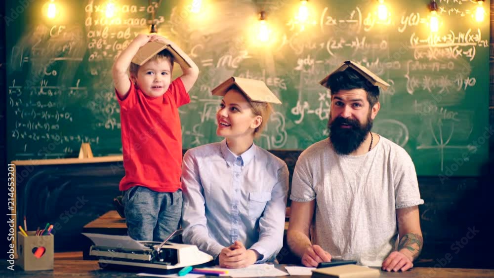 Two adults and a boy with books on the head are entertaining in the ...