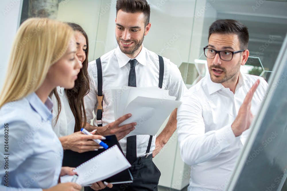 Manager explaining something over flip chart to coworkers in modern ...