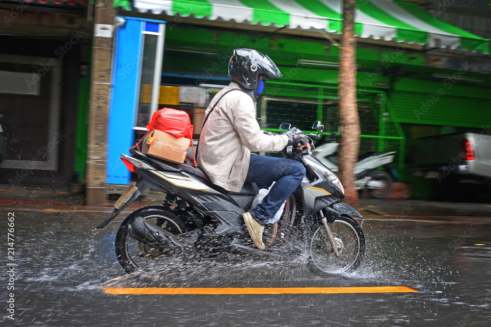 Delivery Motorcycle drive through the flood on the road, flooding in ...