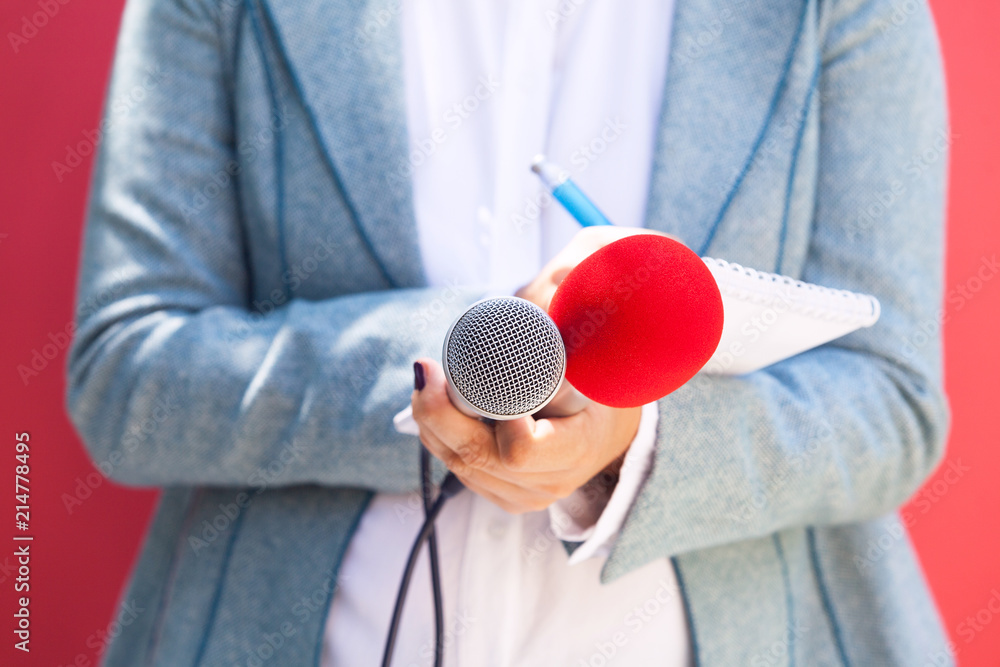 Female journalist at news conference, writing notes, holding microphone ...