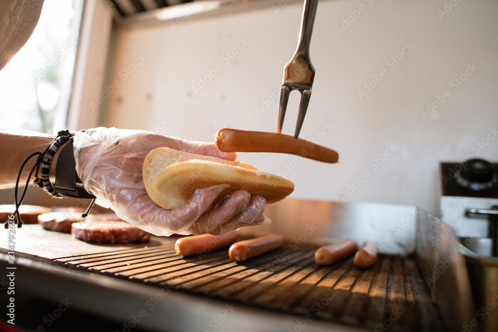 cropped image of chef preparing hod dog in food truck and adding ...
