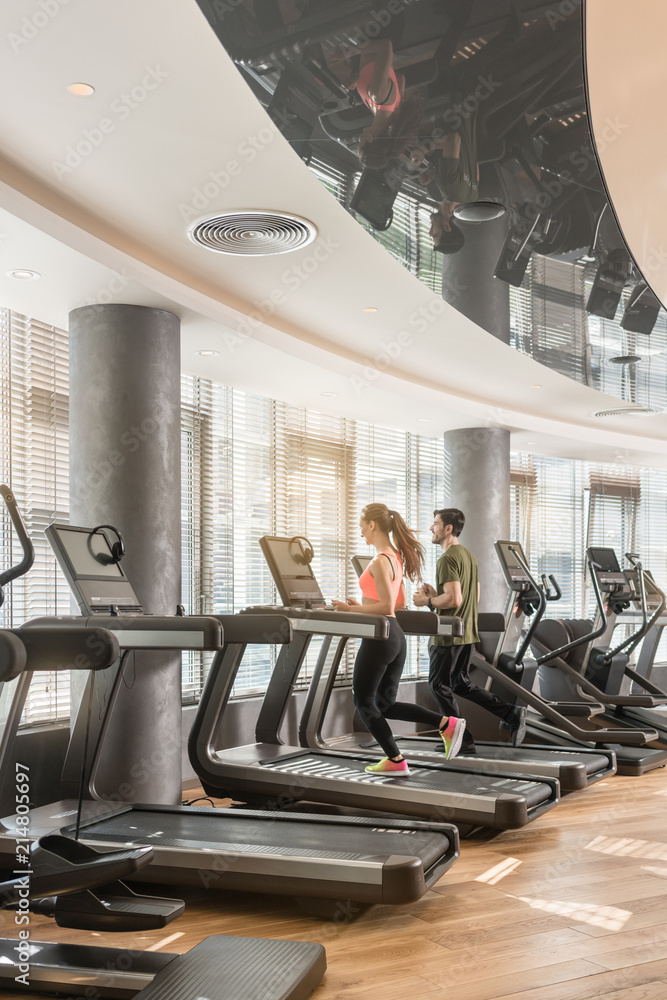 Side view of fit young man and woman smiling while running side by side ...