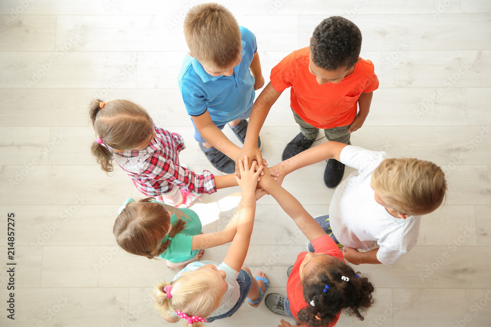 Little children putting their hands together indoors, top view. Unity ...