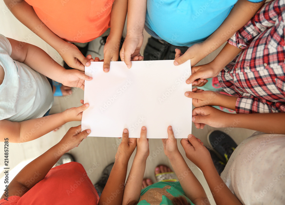 Little children holding sheet of paper in hands together, top view ...