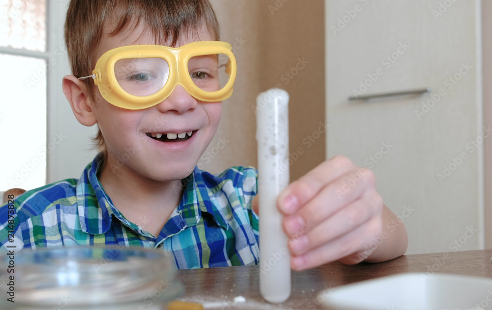 Experiments on chemistry at home. Smiling boy is looking at chemical ...