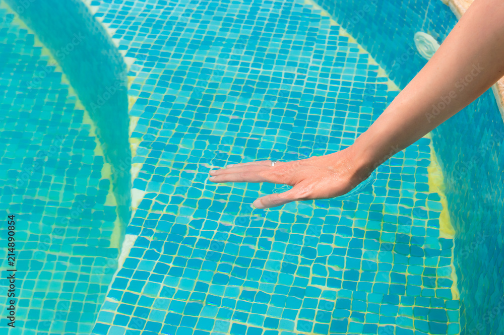 Young girl testing the swimming pool temperature with her hand in the ...