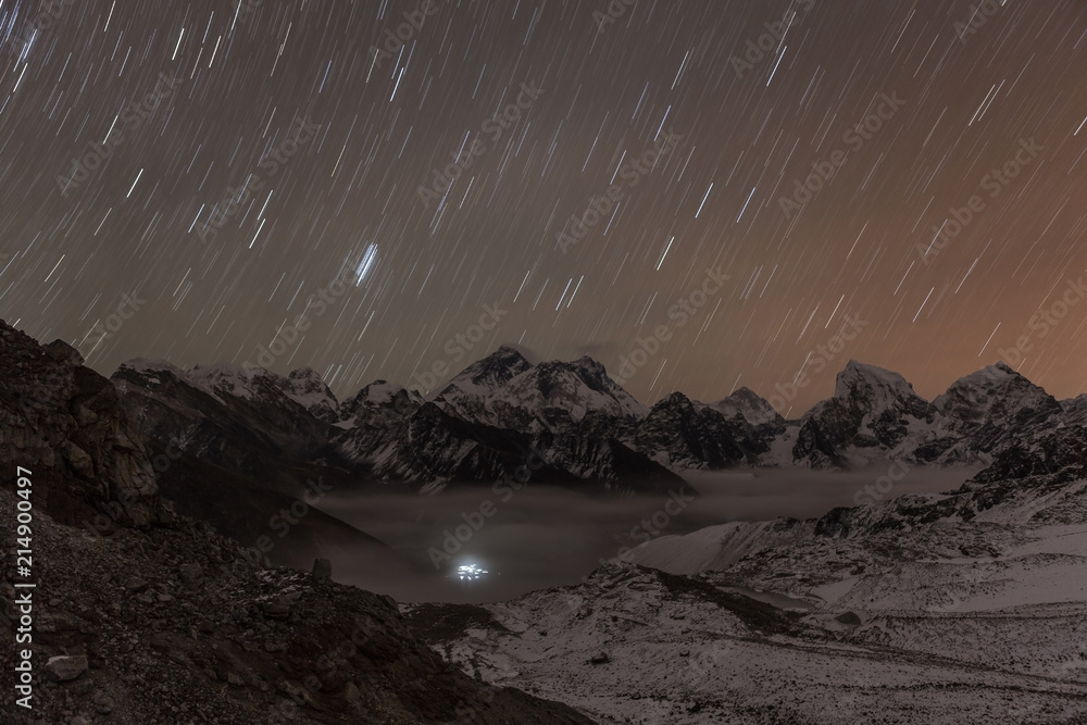 Stars falling above Himalayan mountain range lit up by a bright ...