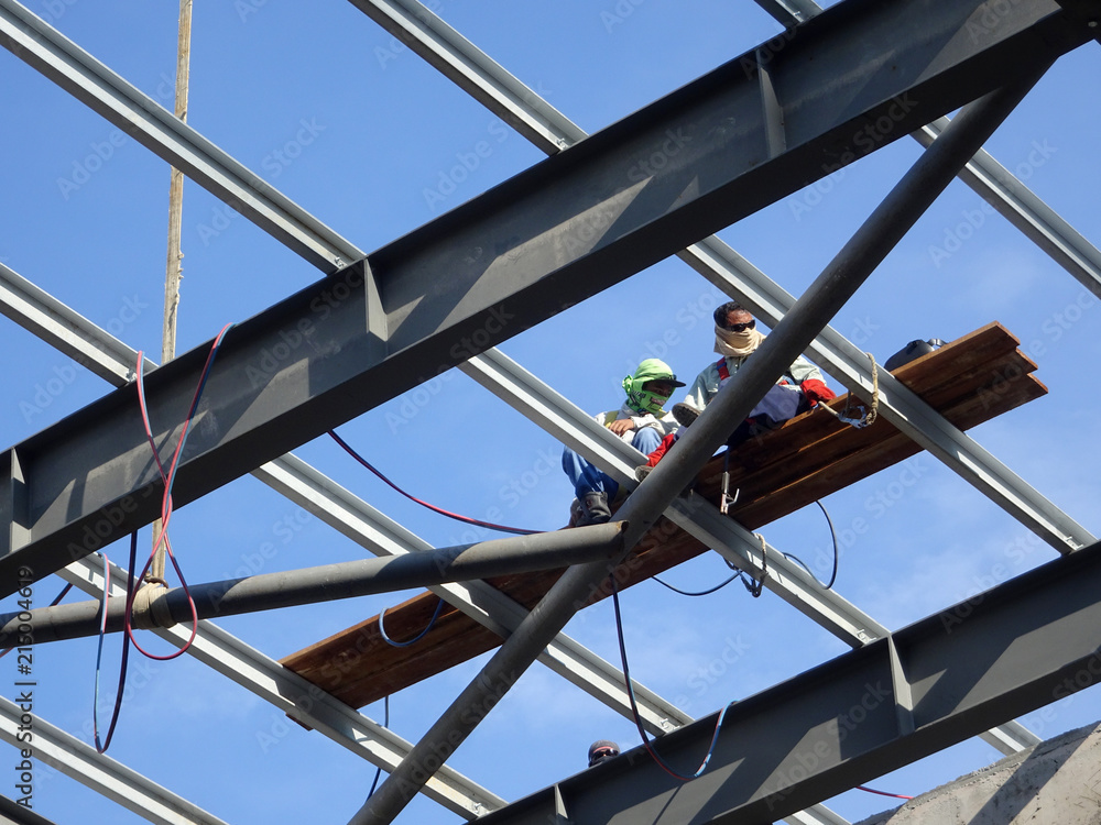 Foto de Metal roof trusses installed by construction workers. The metal ...
