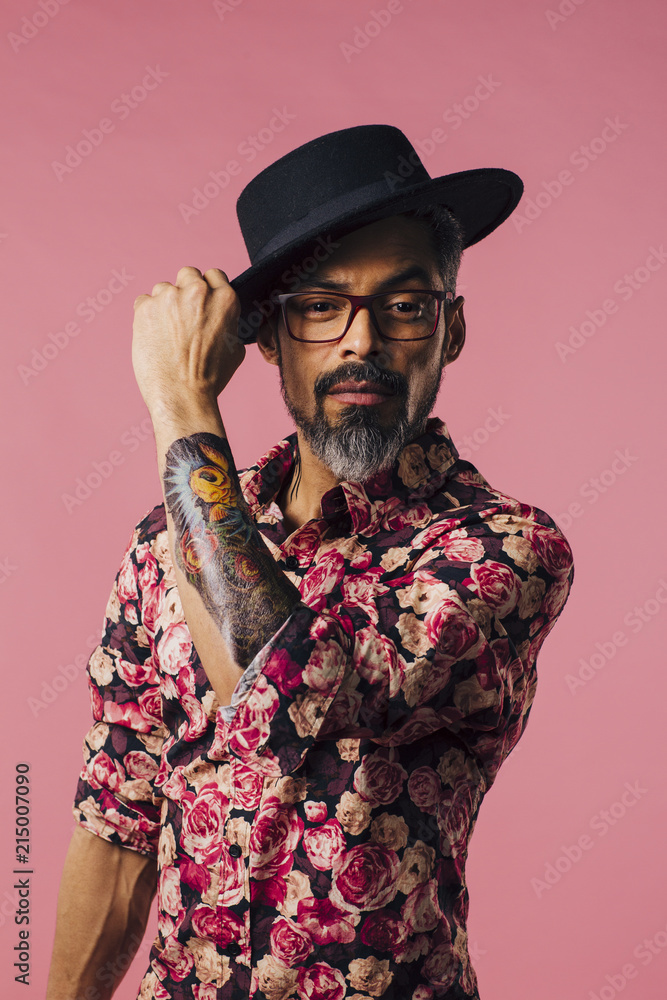 Vertical portrait of a very cool man with tattoos, tilting his hat ...