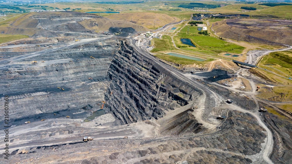 Aerial drone view of a huge opencast coal mine cut into a rural hilly ...