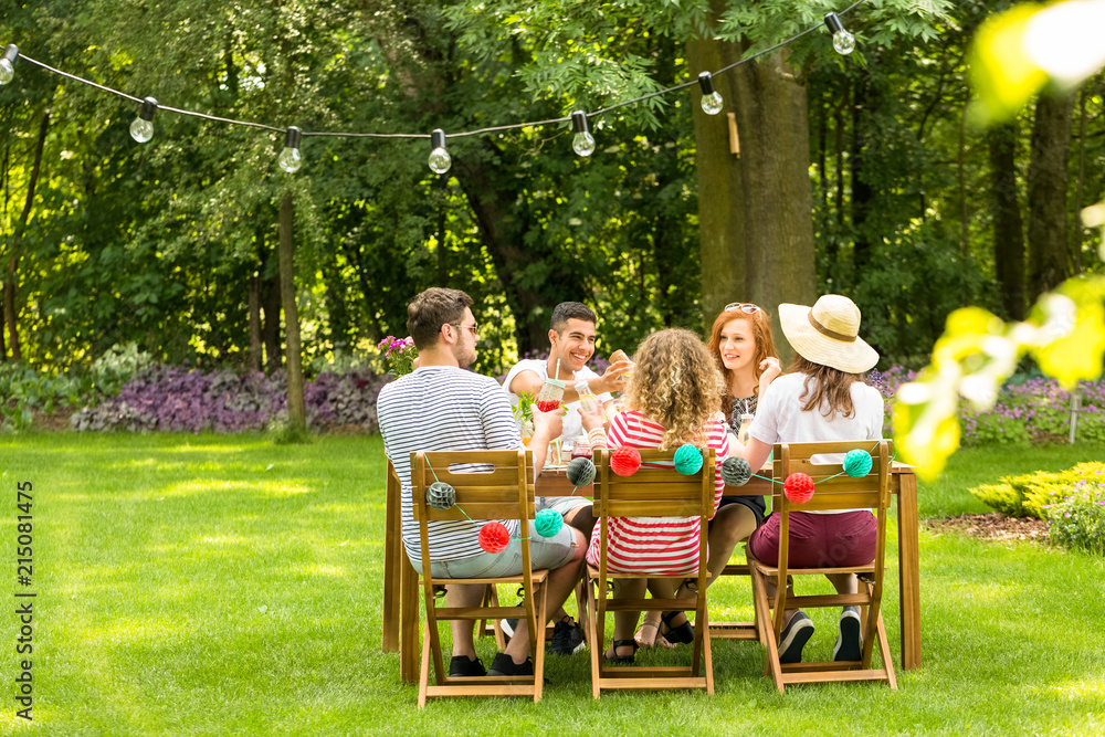 Group of smiling friends enjoying outdoor birthday party during summer ...