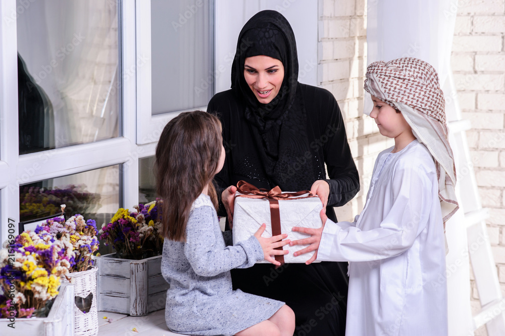 Arabic mother giving gift to her boy and girl.Muslim family. Stock ...