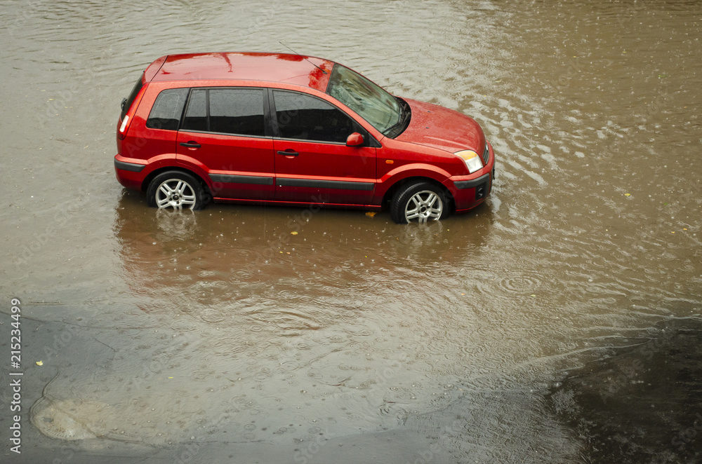 Car in the big puddle under the rain. Raining weather. Flood, the car ...