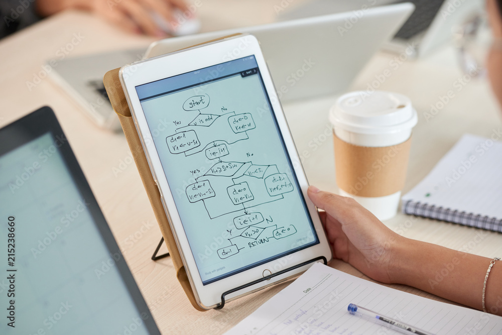 Crop view of female hand holding white tablet with flowchart diagram representing computer ...